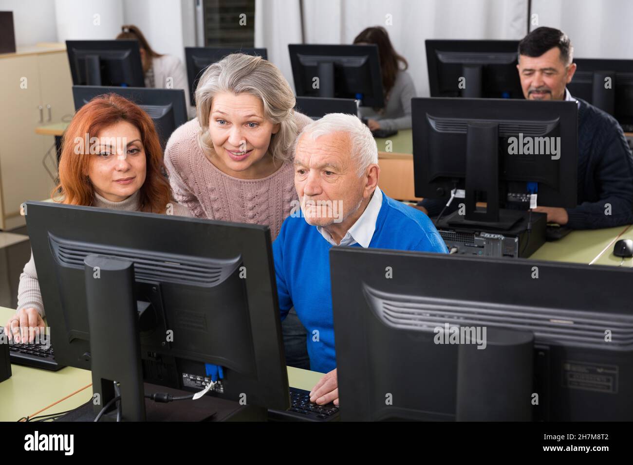 Three coworkers working around computer monitor, talking about new ...