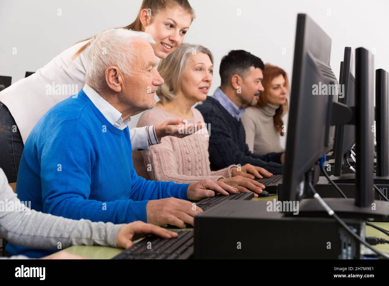 Young female coach giving computer lessons Stock Photo - Alamy