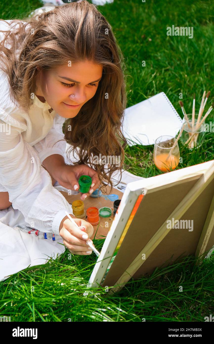 Artist painting on the easel outdoors in the garden. Open air outdoor ...
