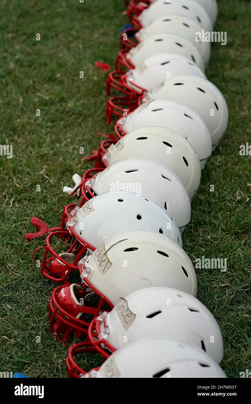 A side view of a group of white football helmets with red face masks ...