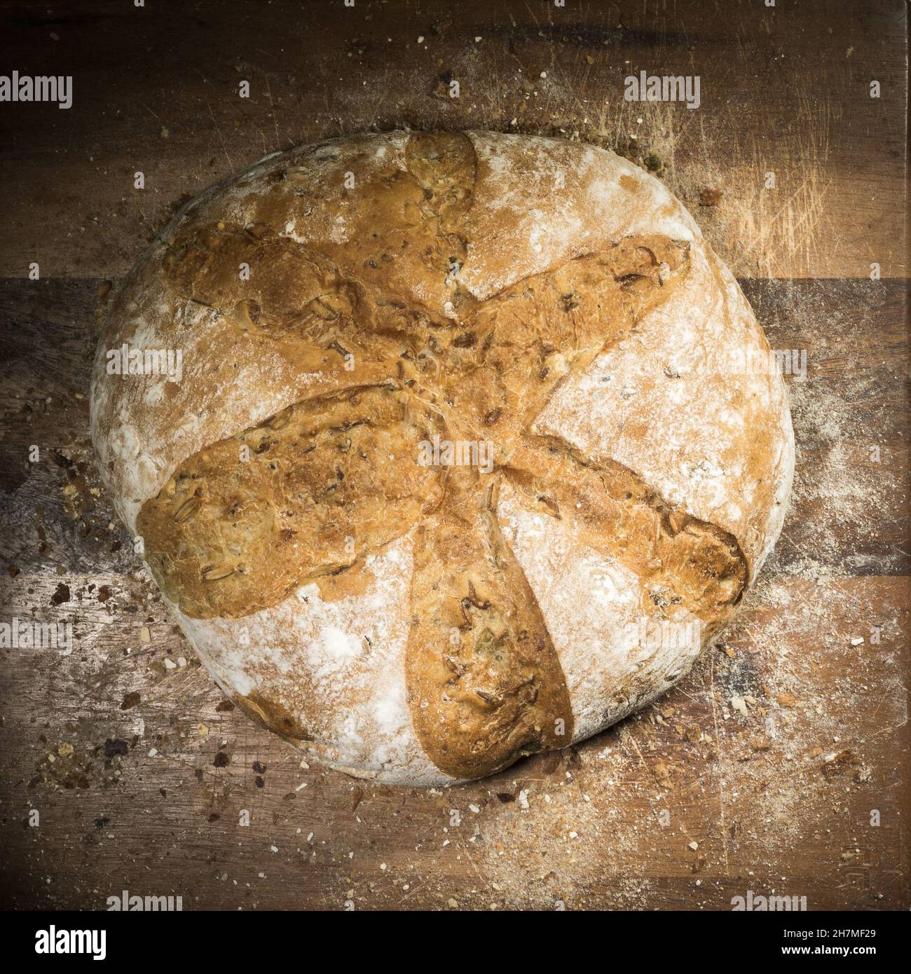 Loaf of bread with cut marks on a wooden cutboard with bread crumbs ...