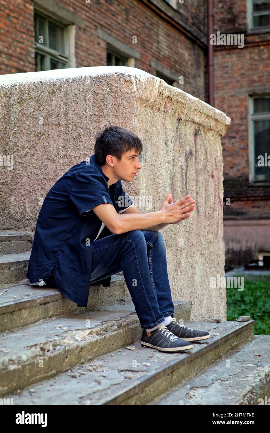Sad Young Man sit on the City Street Stock Photo - Alamy