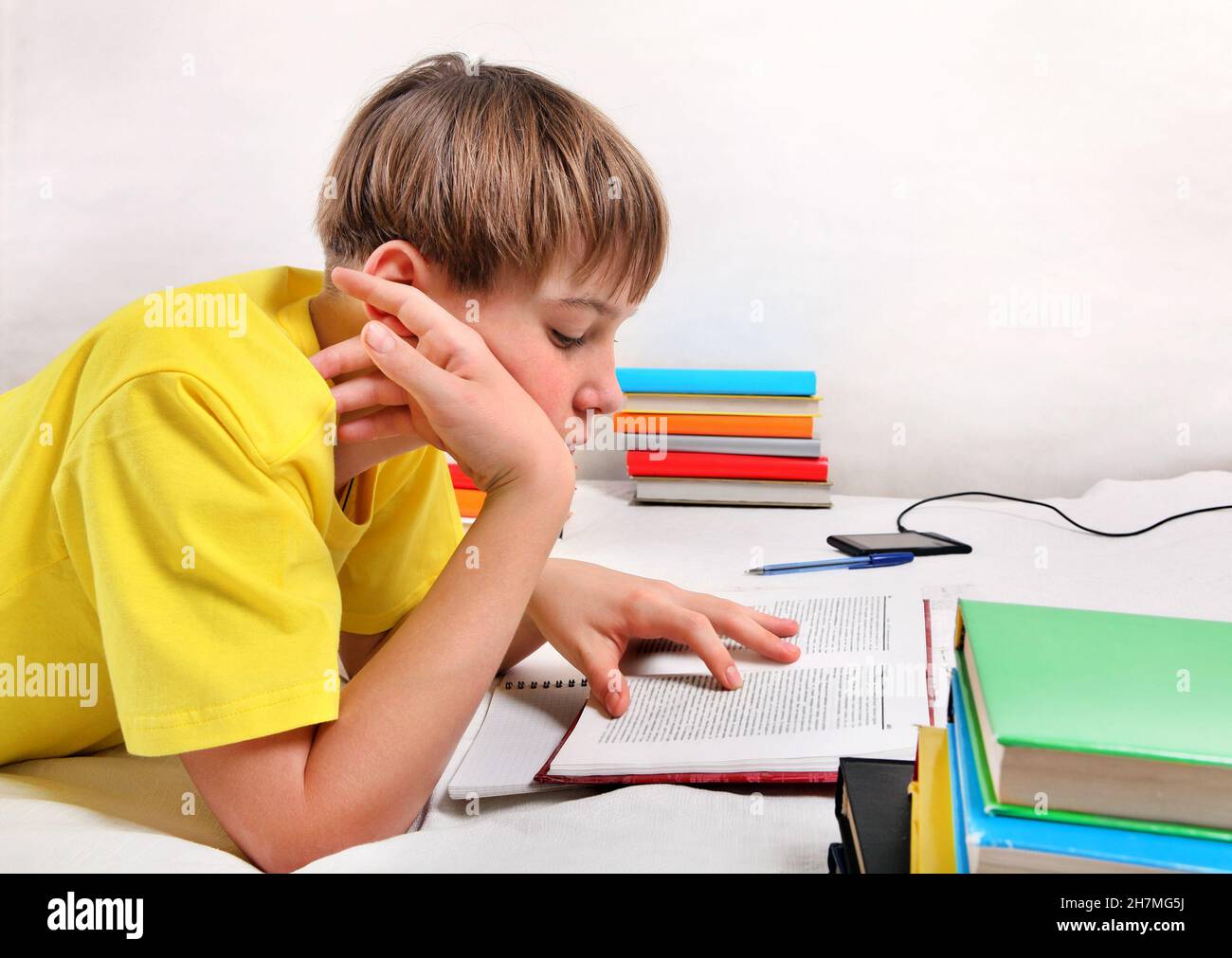 Kid doing Homework on the Bed in the Room Stock Photo - Alamy