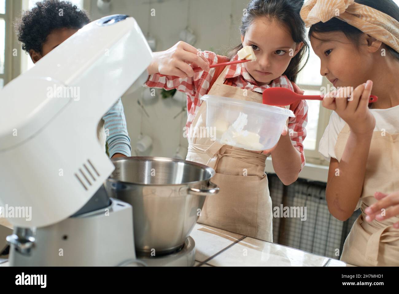 Group of children adding ingredients in the bowl and making cream for ...