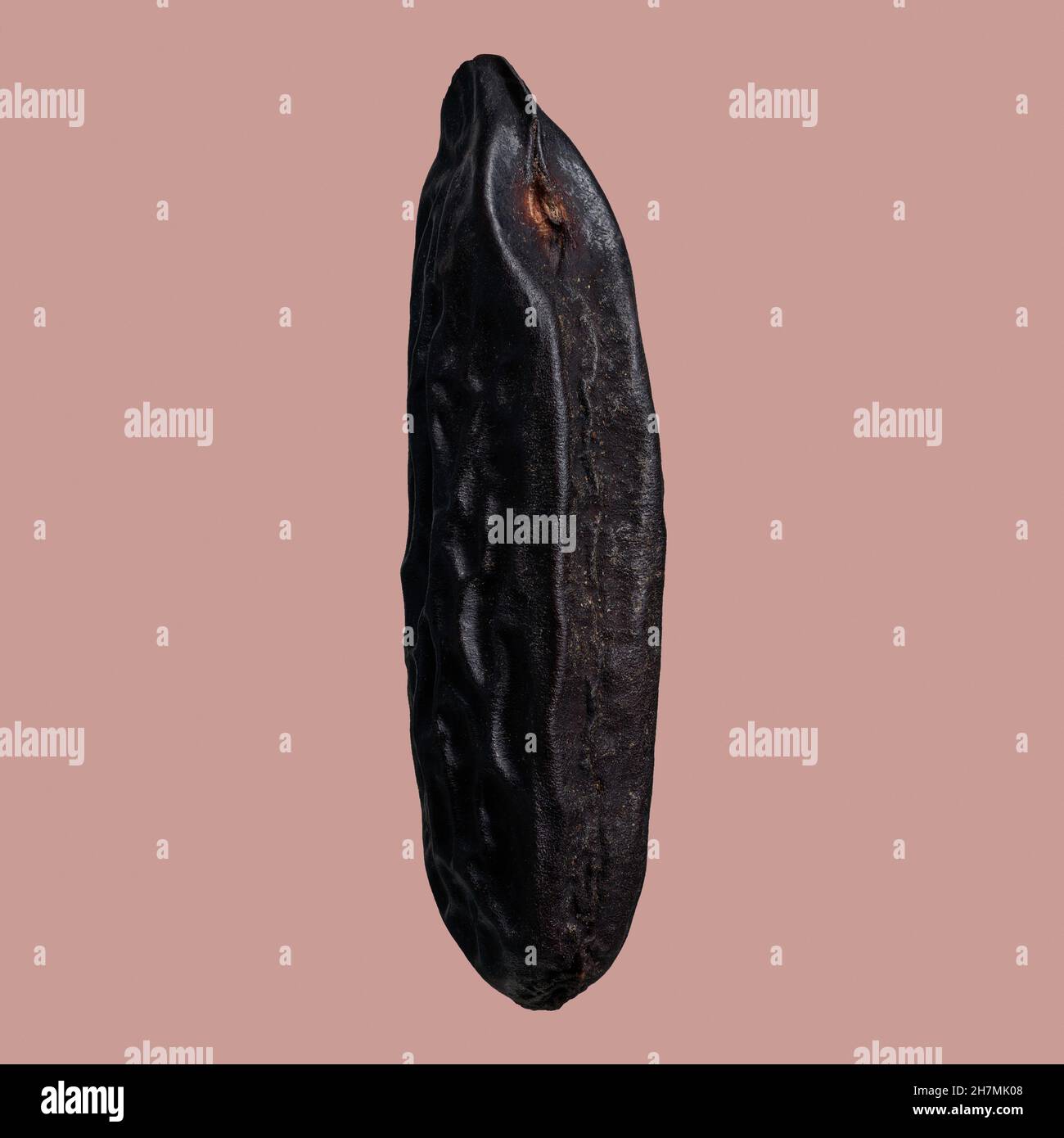 Close up black tonka bean on pink background Stock Photo - Alamy