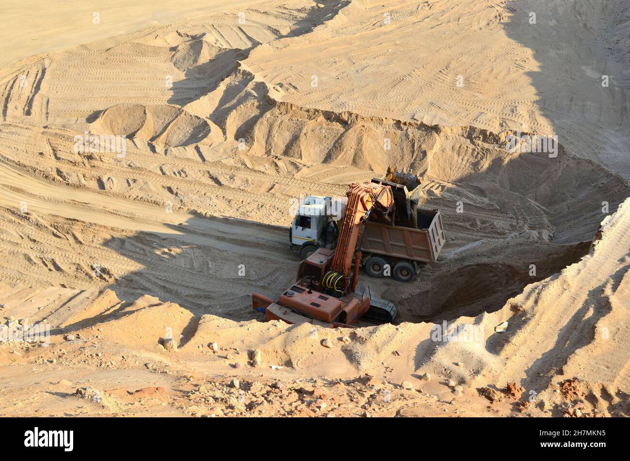 Excavator developing the sand on the opencast and loading it to the ...