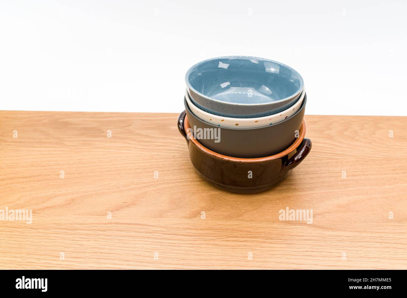 colorful piled up empty stoneware bowls on a wooden tabletop with copy ...