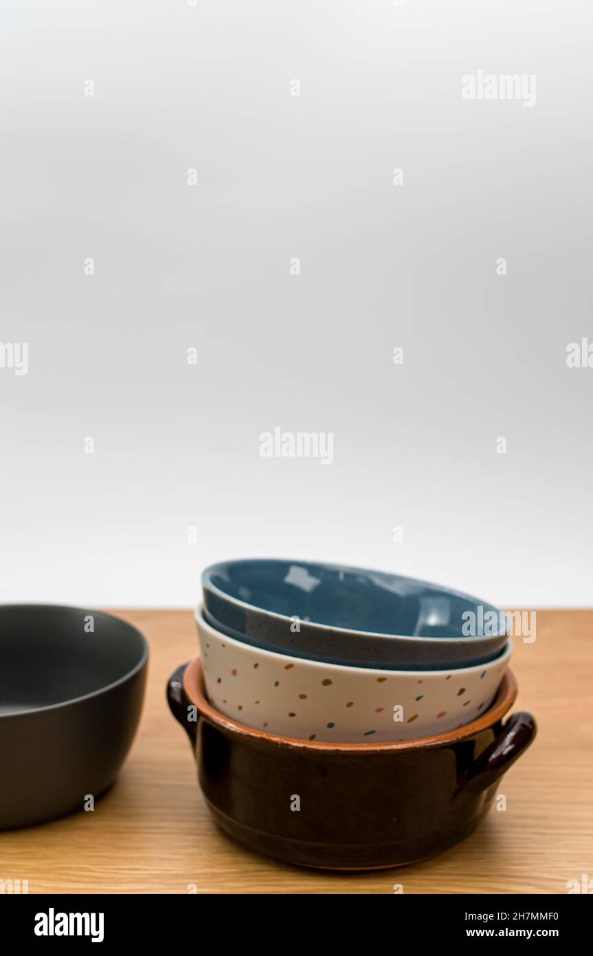 colorful piled up empty stoneware bowls on a wooden tabletop with copy ...