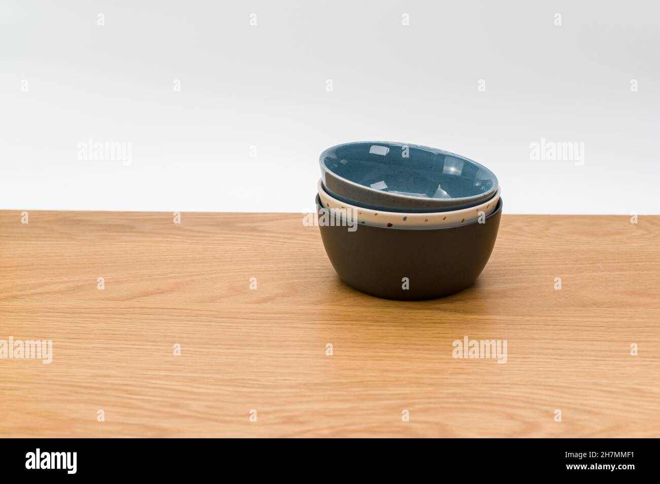 colorful piled up empty stoneware bowls on a wooden tabletop with copy ...