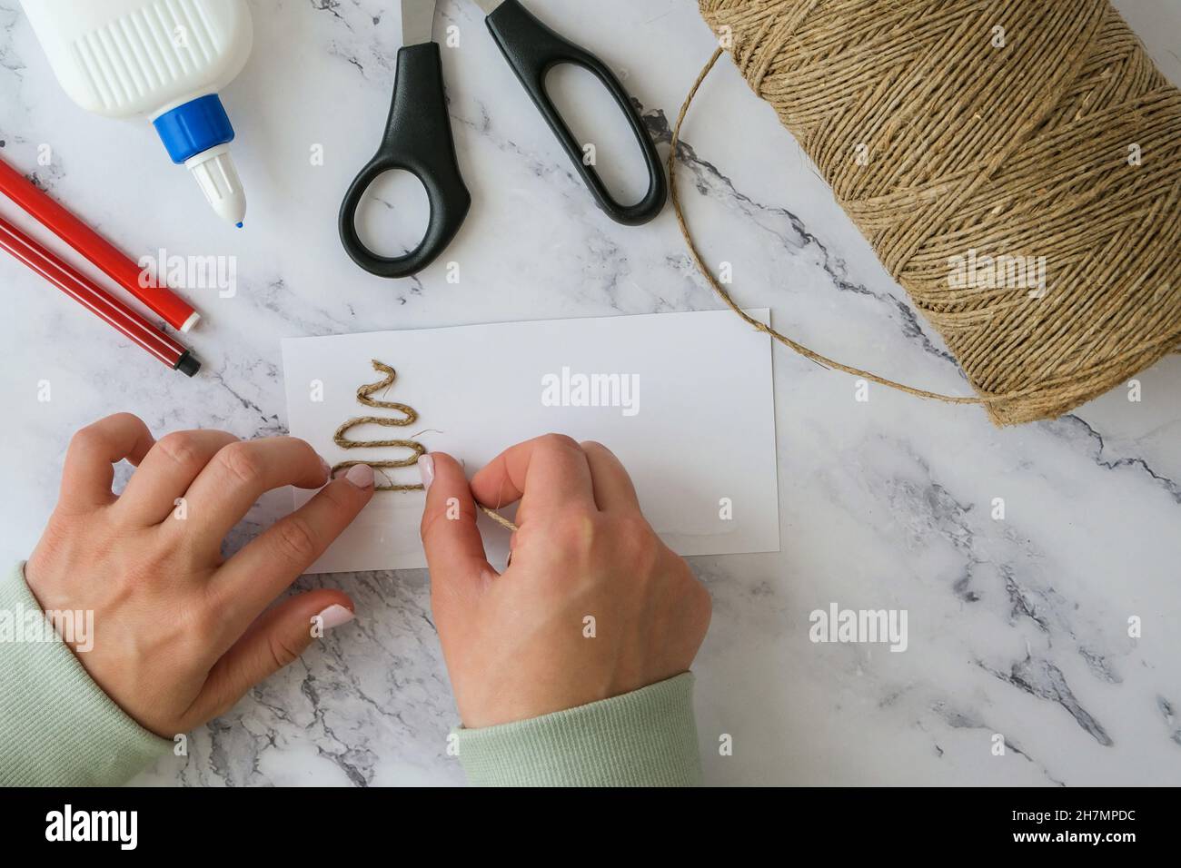Christmas tree made of rope. Top view of hands making step by step ...