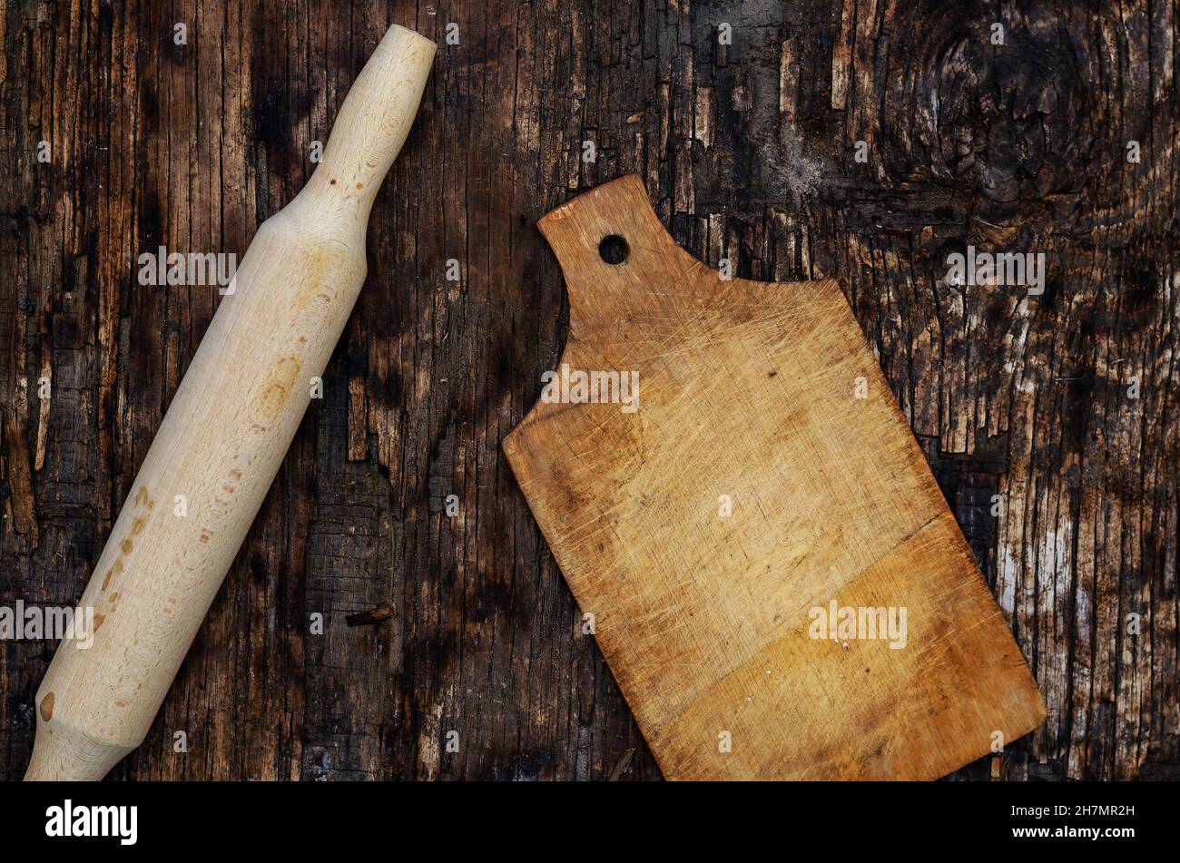 Wooden rolling pin and cutting board on a dark burnt wooden surface ...