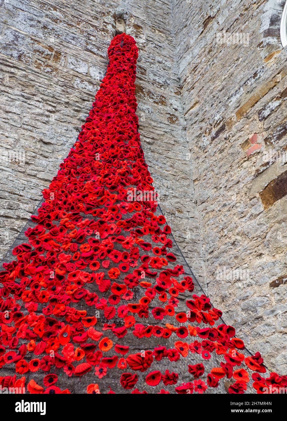 Cascade of knitted poppies on the 13th century tower of the church of ...