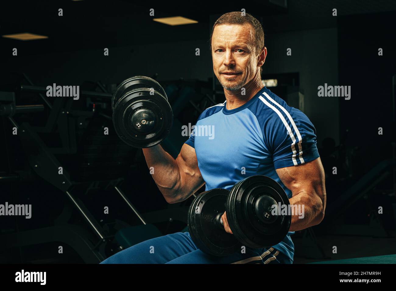 Fit senior man exercising with dumbbells in a gym Stock Photo - Alamy