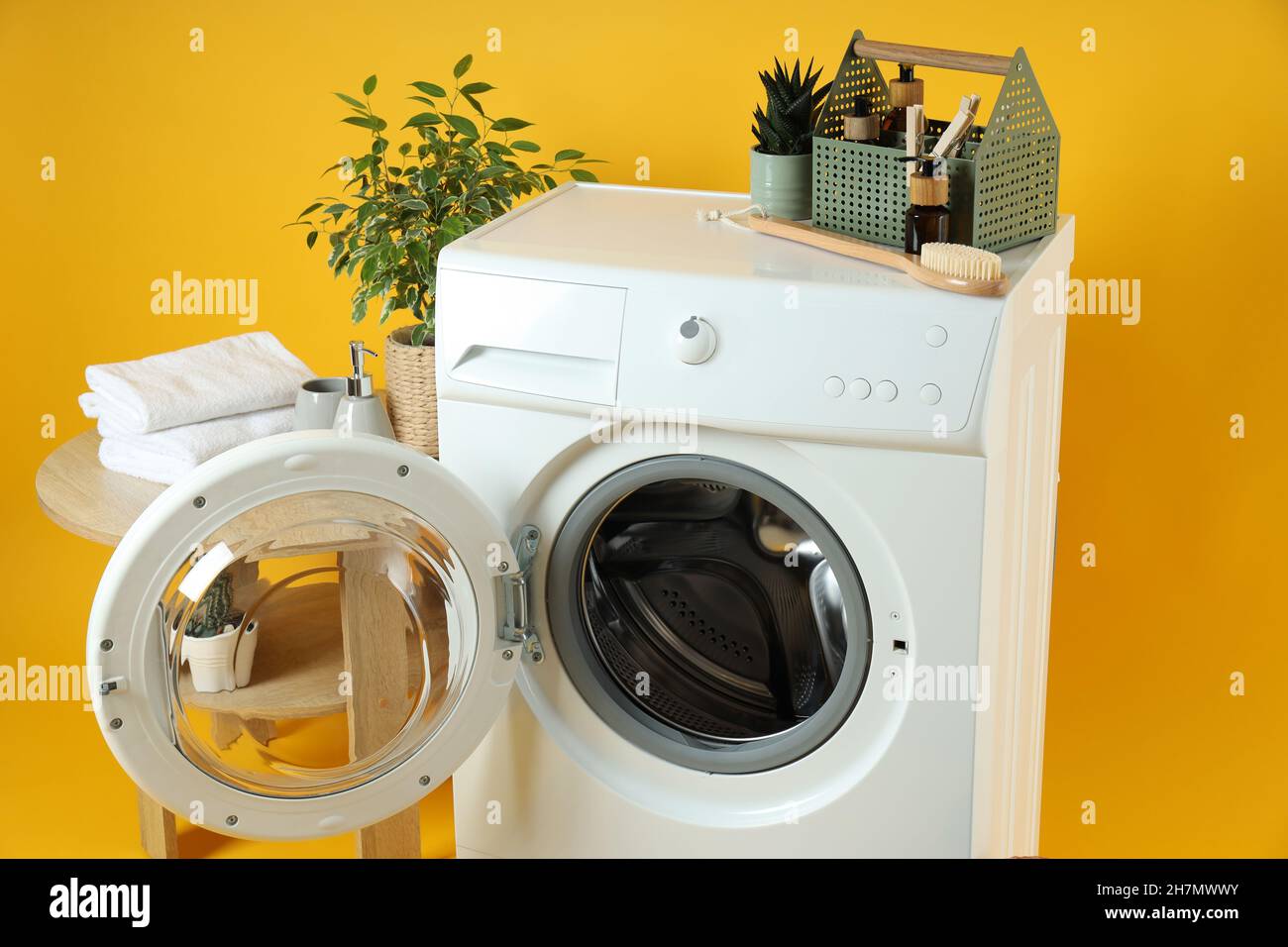 Concept of housework with washing machine on yellow background Stock ...