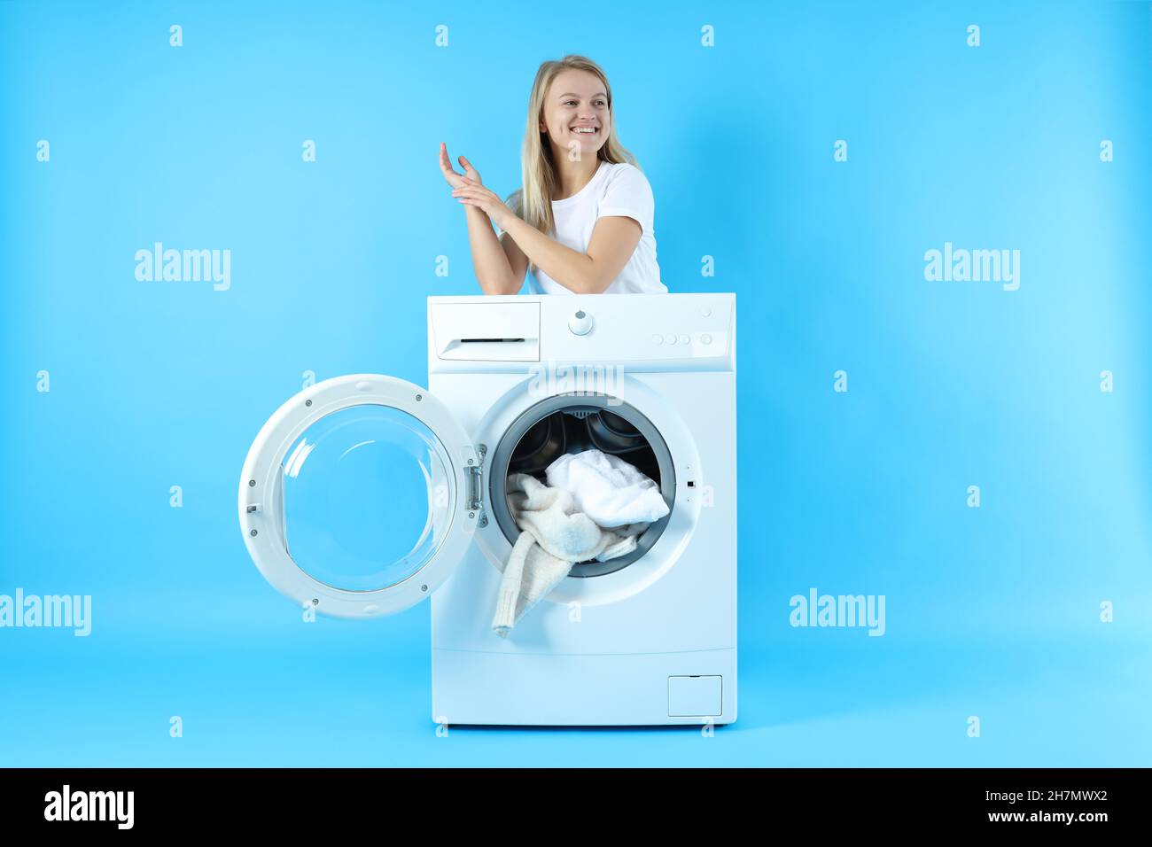 Concept of housework with washing machine and girl on blue background ...