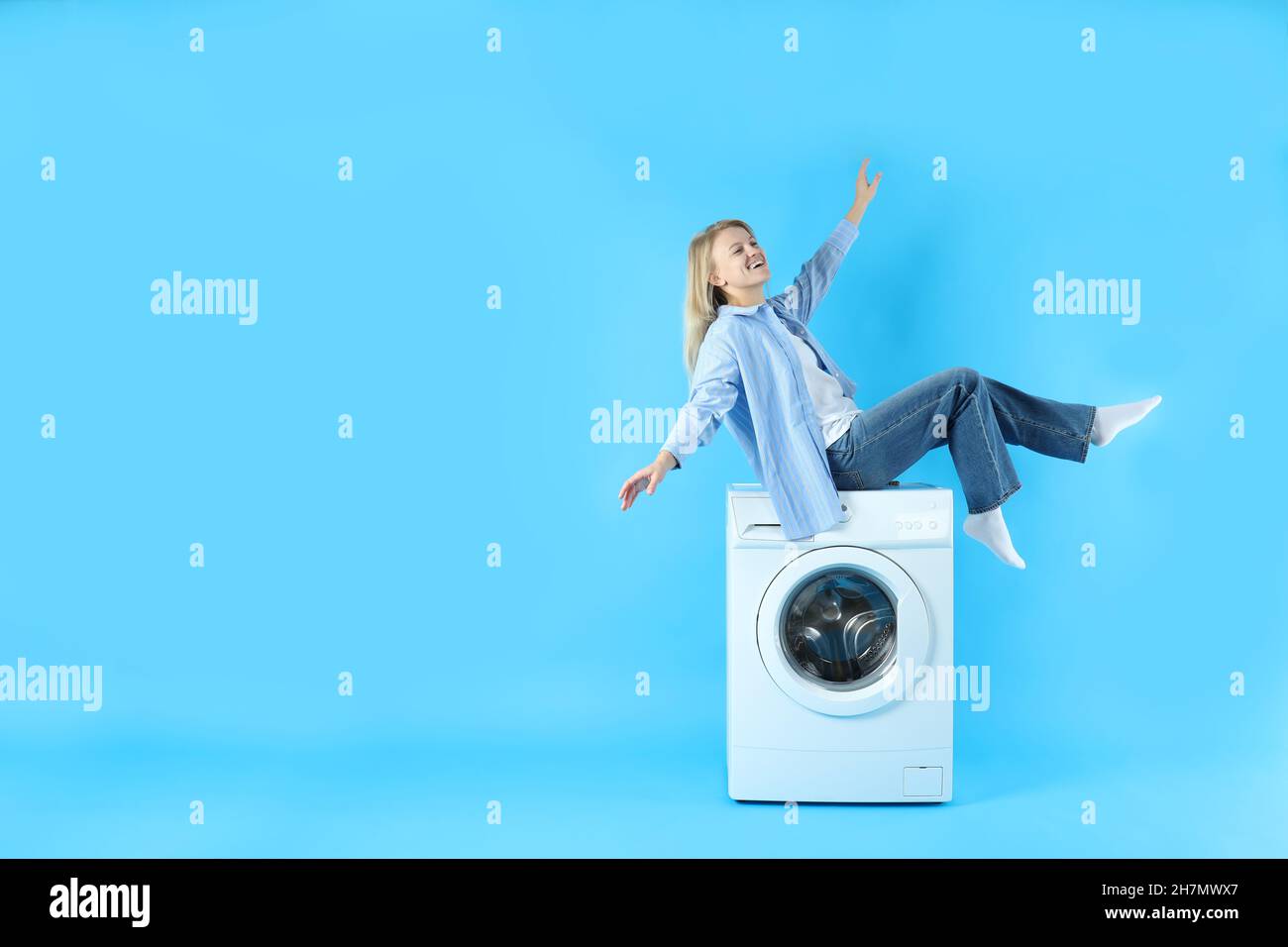 Concept of housework with washing machine and girl on blue background ...