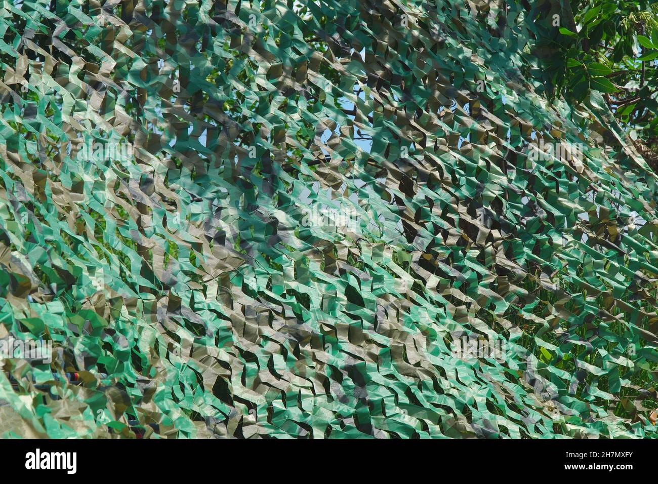 Military green camouflage net masking and covering a secret object ...