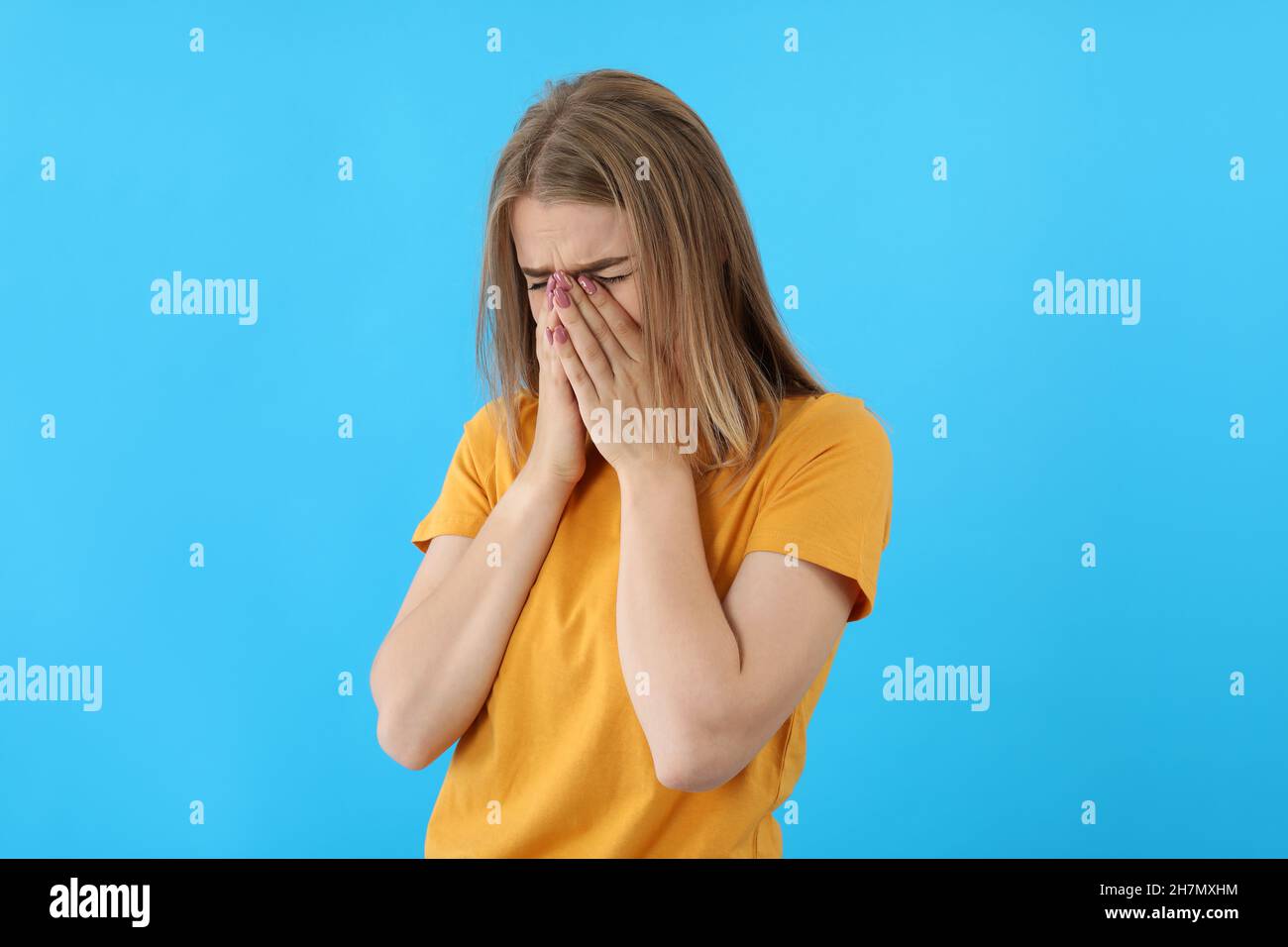 Crying girl in t-shirt on blue background Stock Photo - Alamy