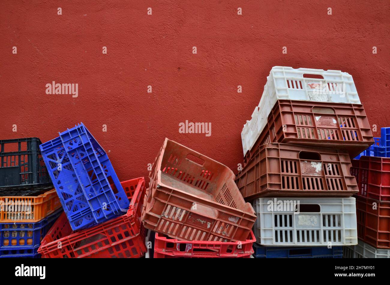 Plastic boxes, plastic baskets in front of red wall, wildly stacked ...