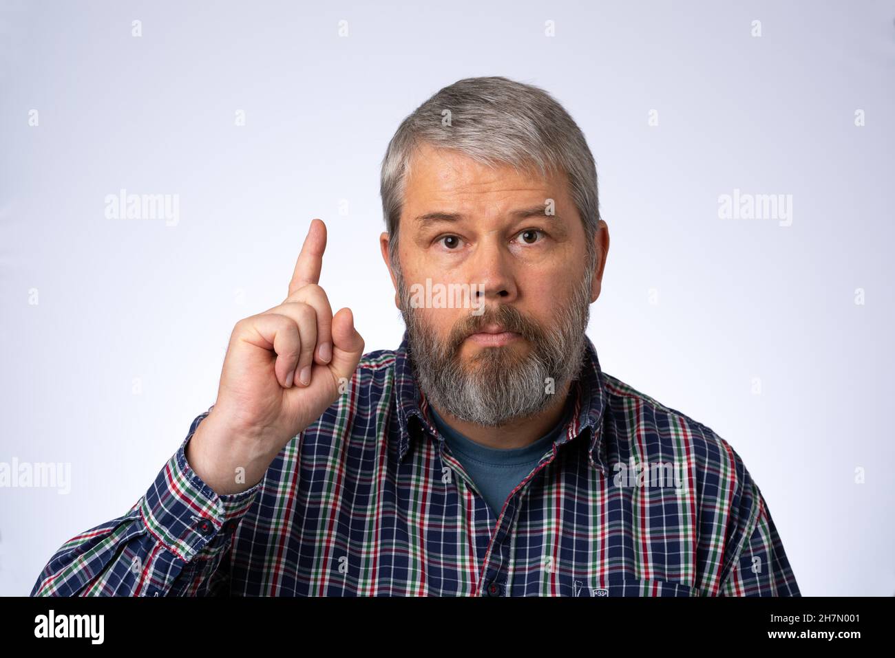 Man with full beard, 54 years old, raises his index finger in a ...