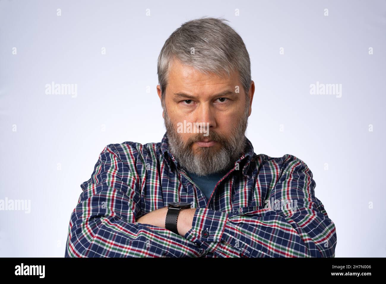 Man with full beard, 54 years, looks annoyed, angry into camera, arms ...