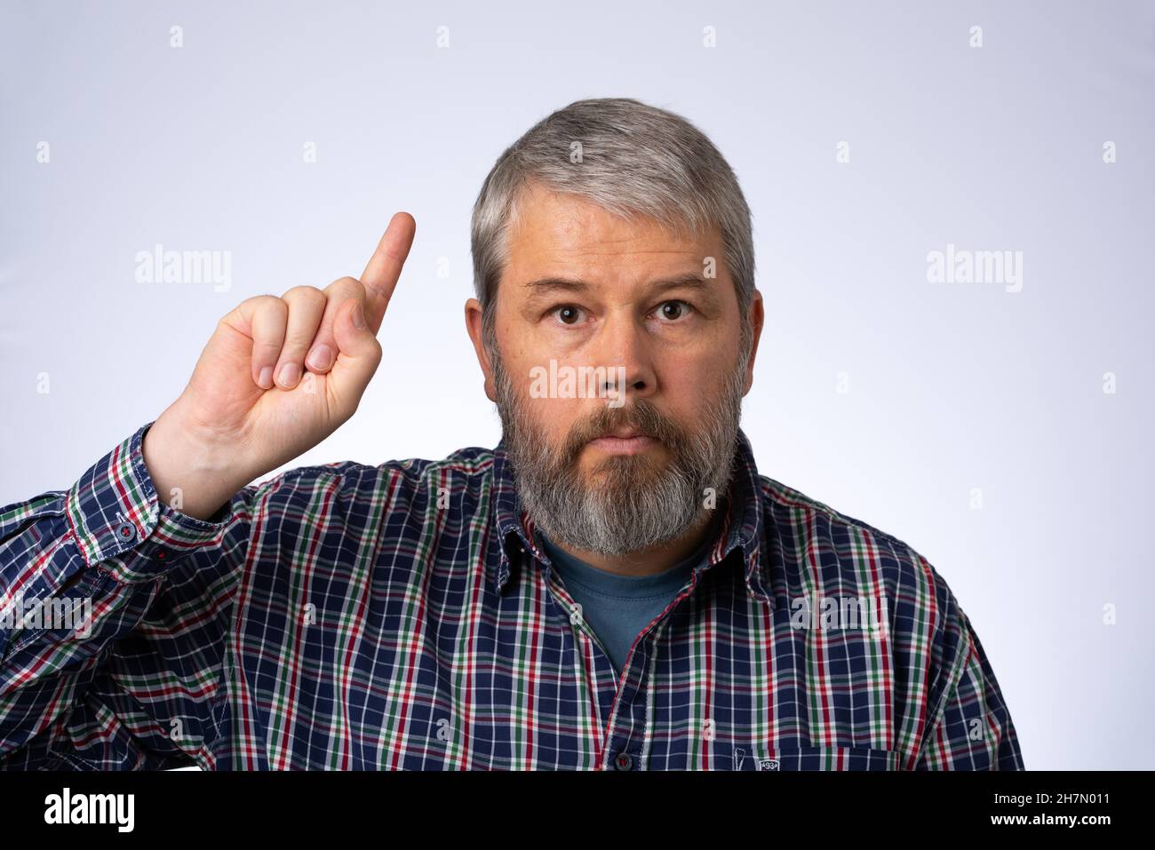 Man with full beard, 54 years old, raises his index finger in a ...