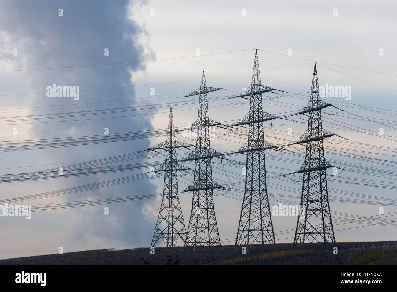 High-voltage pylons, electricity pylons in front of water vapour cloud ...