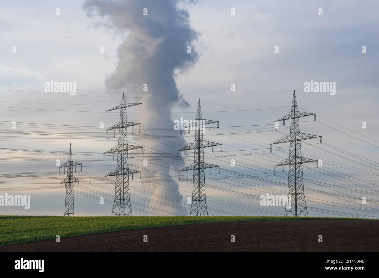 High-voltage pylons, electricity pylons in front of water vapour cloud ...