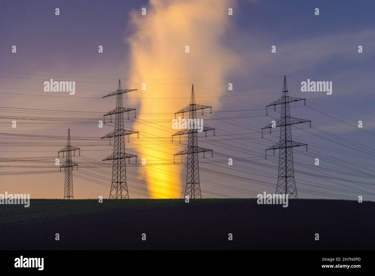 High-voltage pylons, electricity pylons in front of water vapour cloud ...