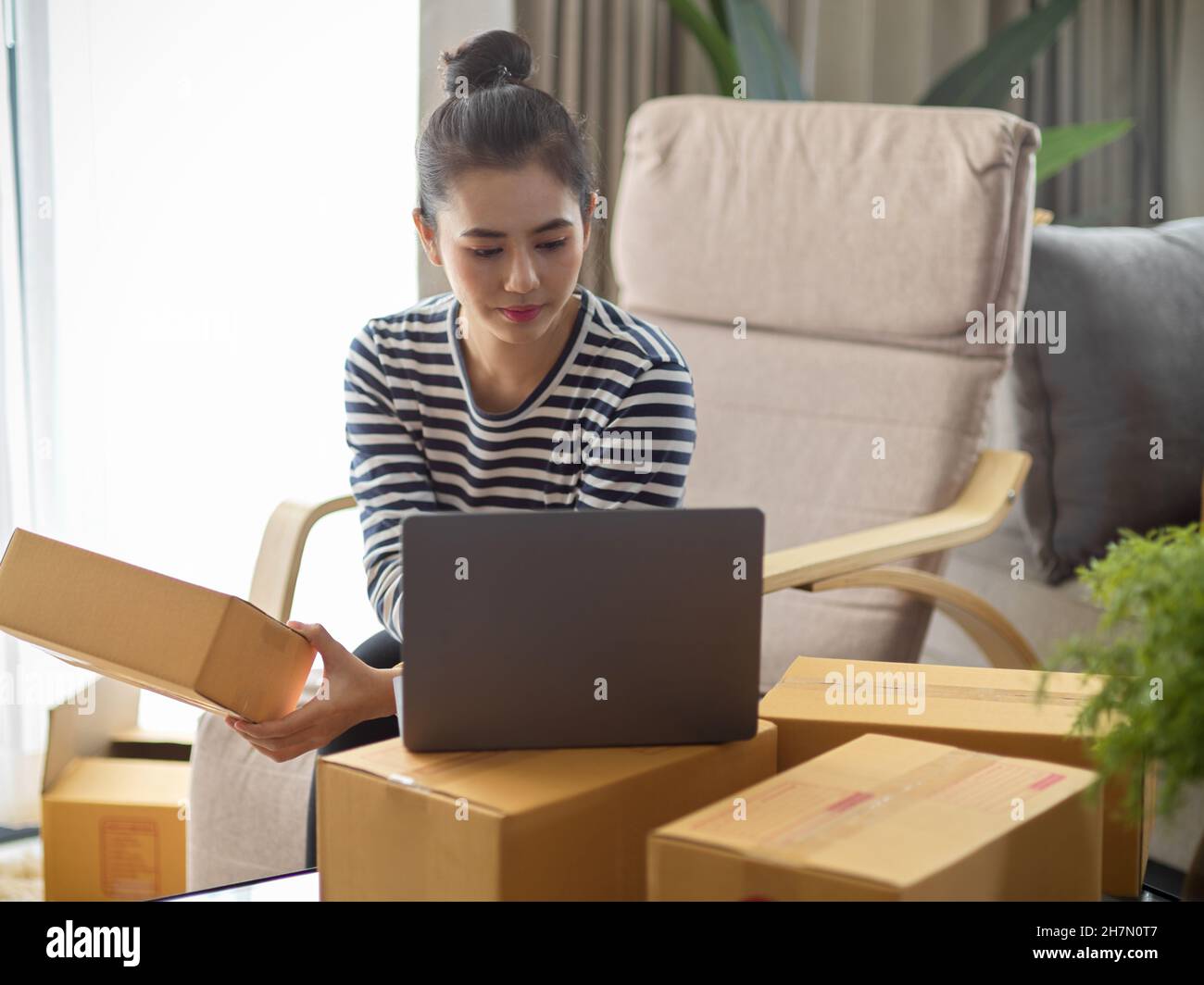 A successful SME business entrepreneur works on her laptop computer ...