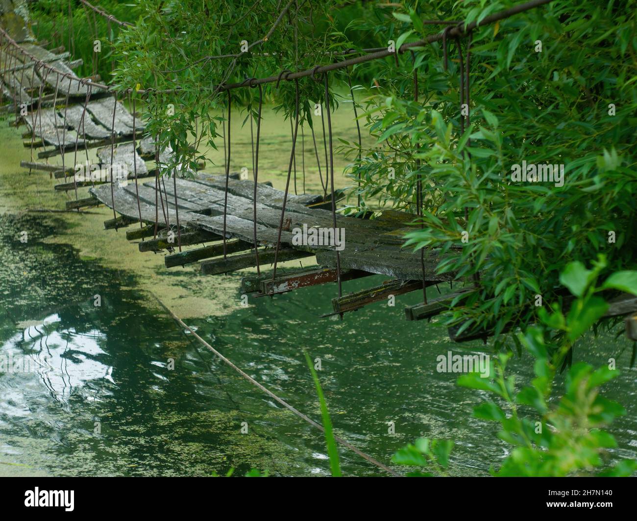 a collapsed wooden pedestrian bridge over the river, in summer Stock ...