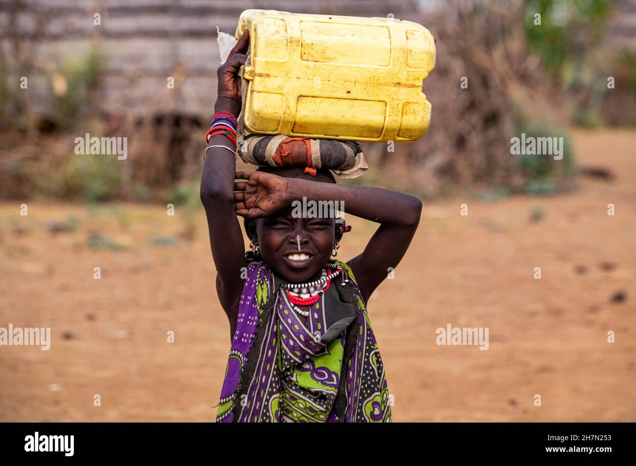 Traditional dressed girl carrying a water container, Jiye tribe ...