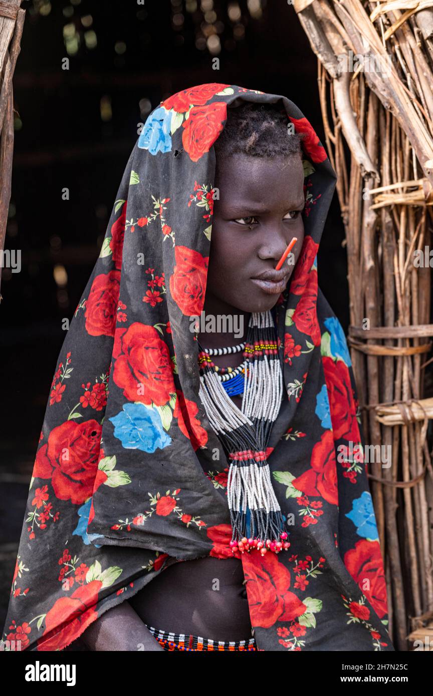 Traditional dressed child of the Jiye tribe sitting in her hut, Eastern ...