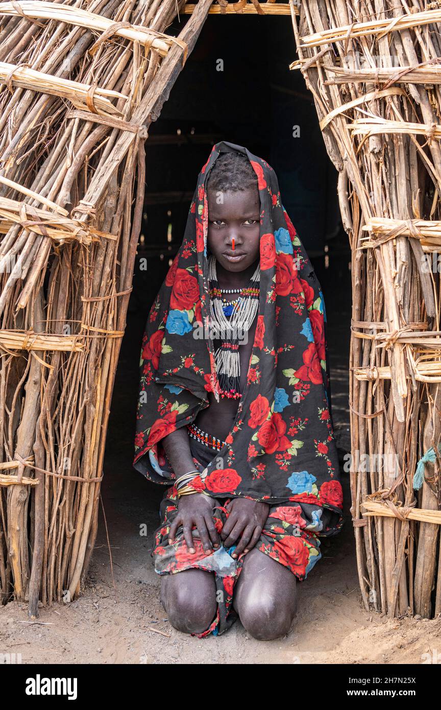 Traditional dressed child of the Jiye tribe sitting in her hut, Eastern ...