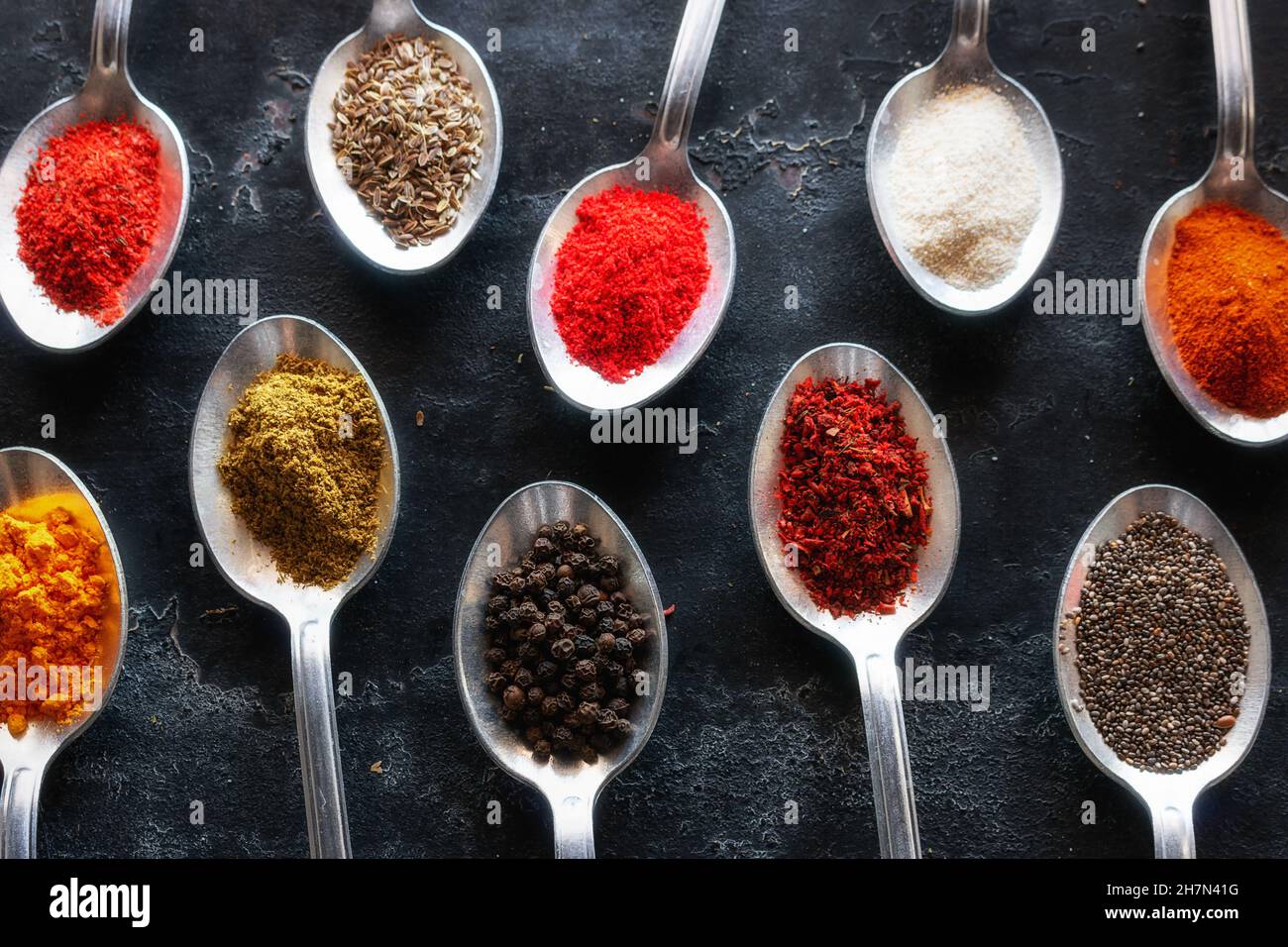 spices and herbs in tablespoons on a black kitchen table close-up Stock ...
