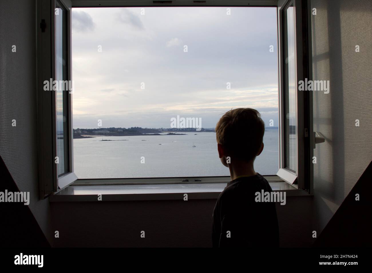 Young boy looking at the window Stock Photo - Alamy