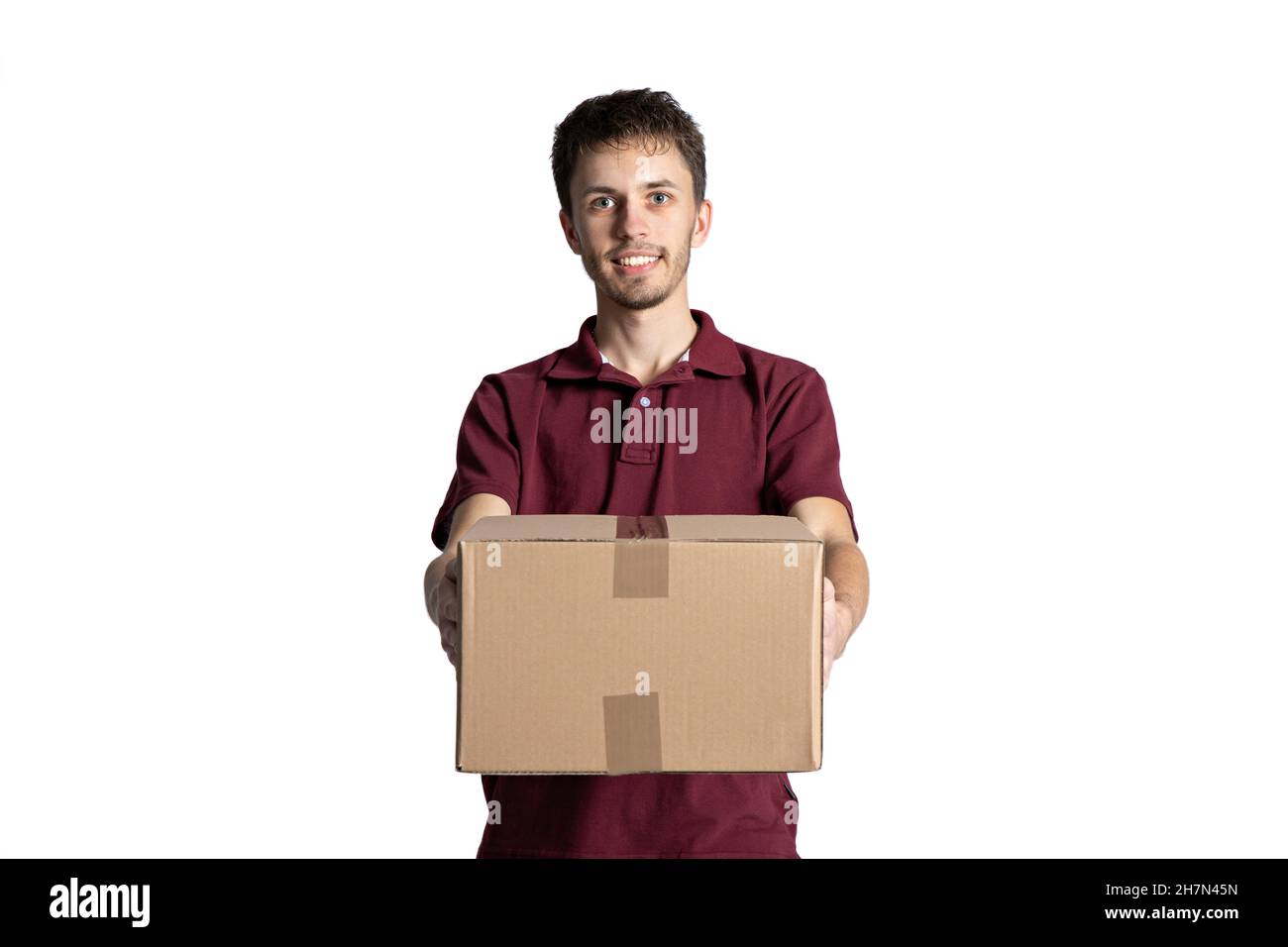 Smiling delivery man holding pile of cardboard boxes on a white ...