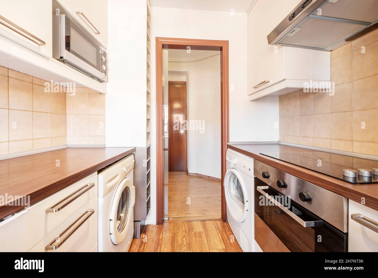 Kitchen with wood-colored countertop, open dishwasher, ceramic hob ...
