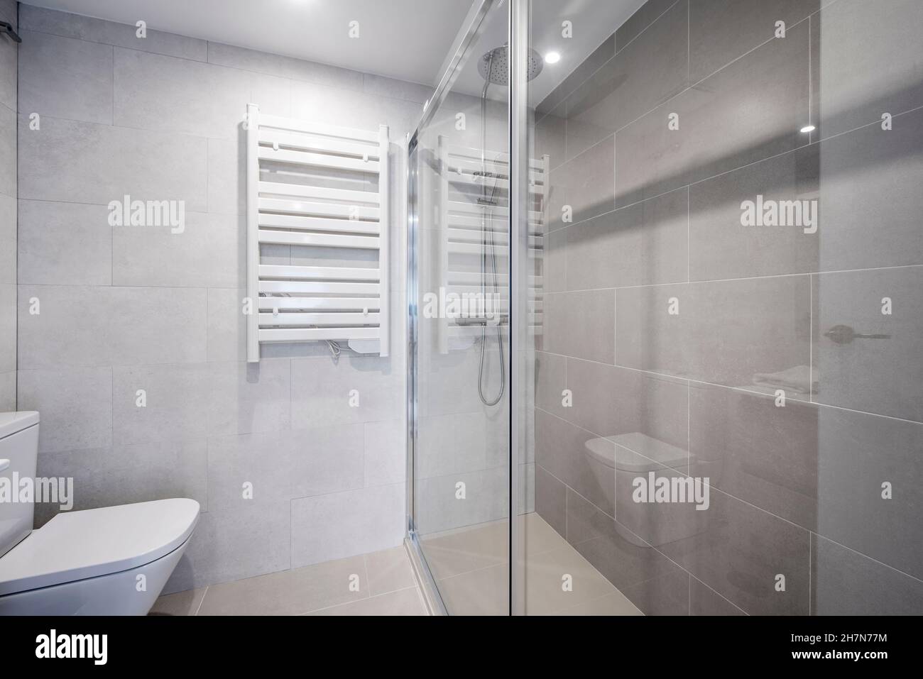Shower with screen and radiator on the wall in a bathroom with gray ...