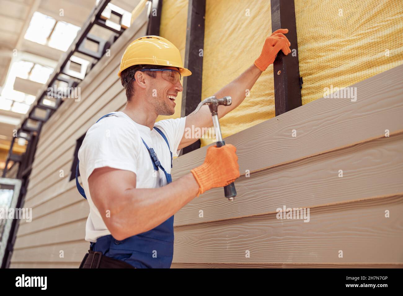 Joyful male builder using hammer at construction site Stock Photo - Alamy