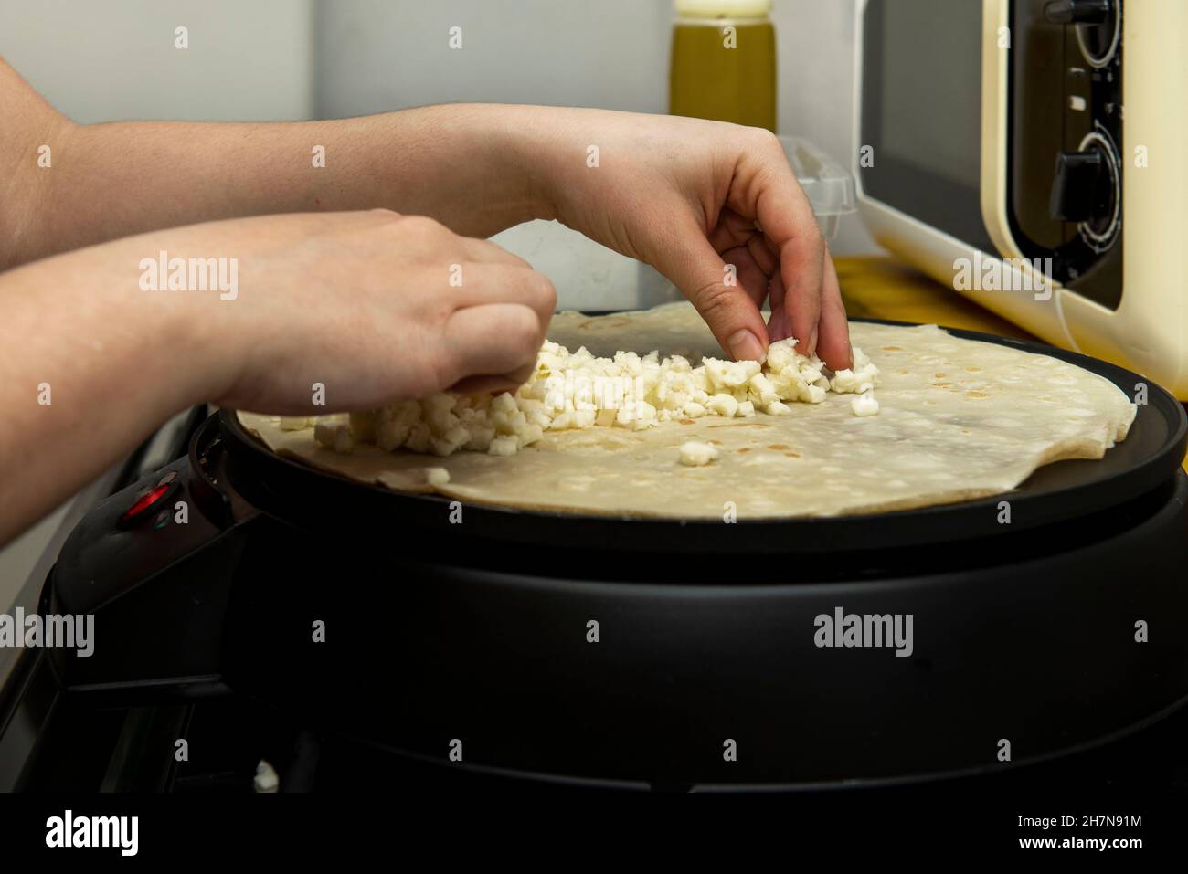 Female chef hands placing grated cheese on top of a pancake being ...