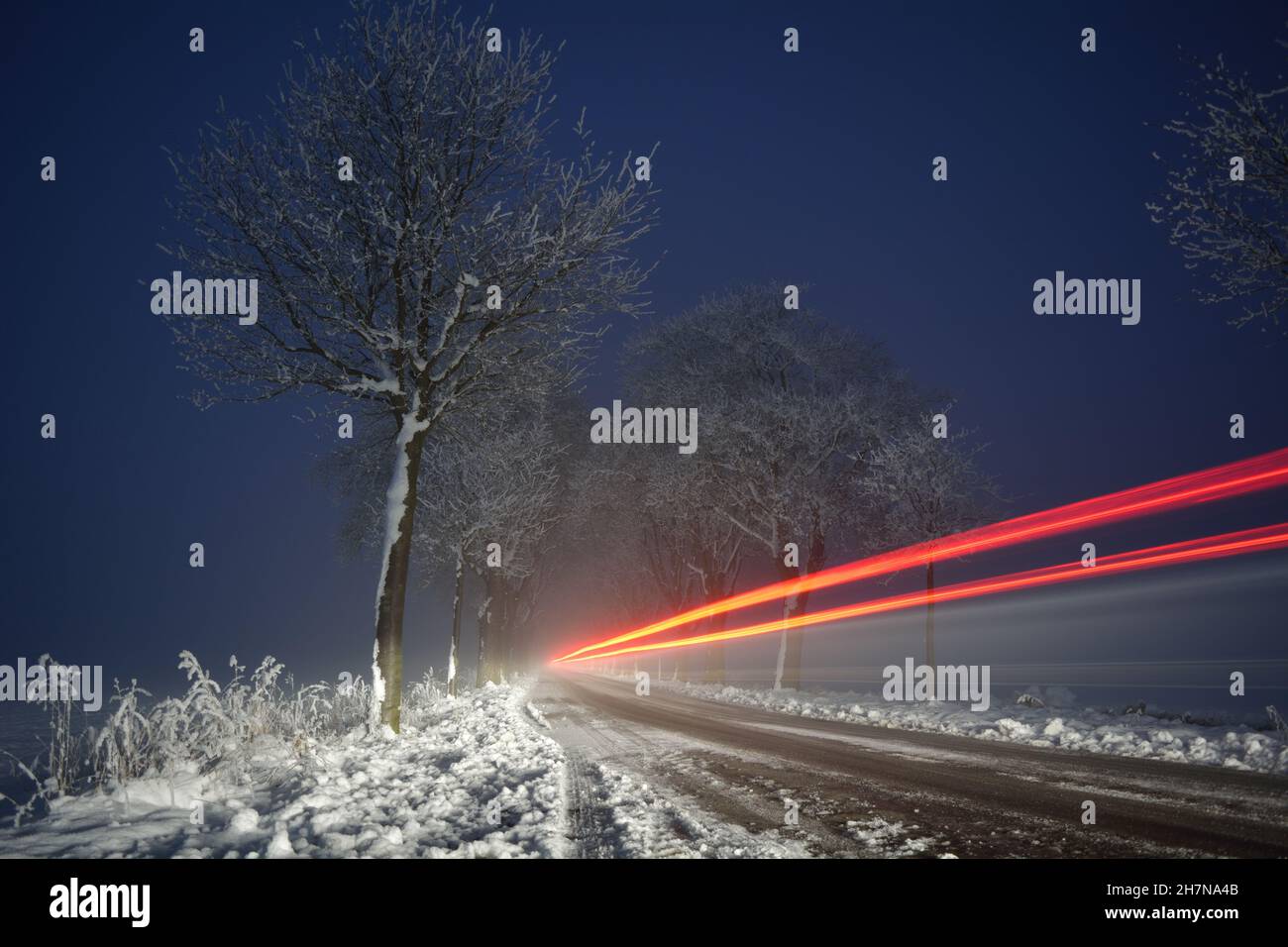 A Car Driving Trough a Snowy Avenue Stock Photo - Alamy