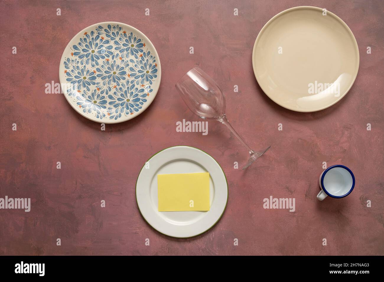Different plates with a note on one of them, glass goblet and white cup ...