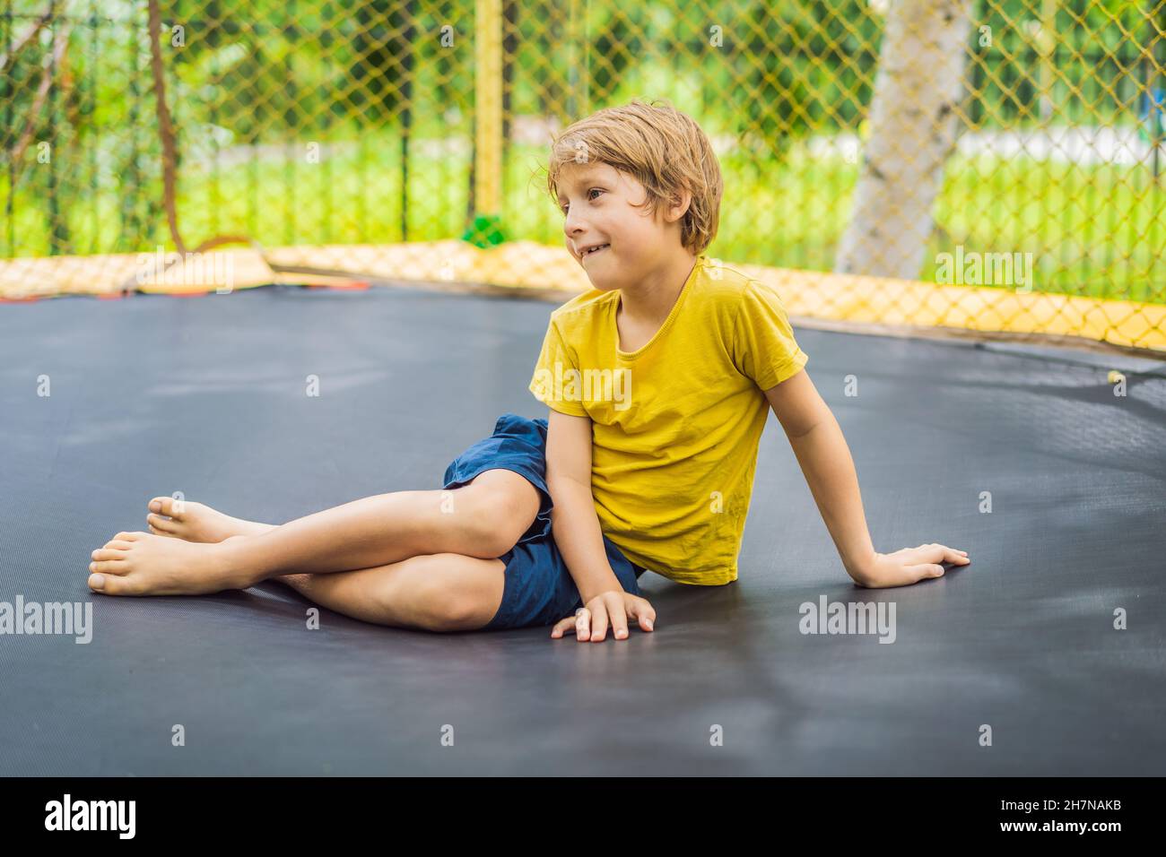 Happy boy plays outdoors in garden jumping high in the sky on ...