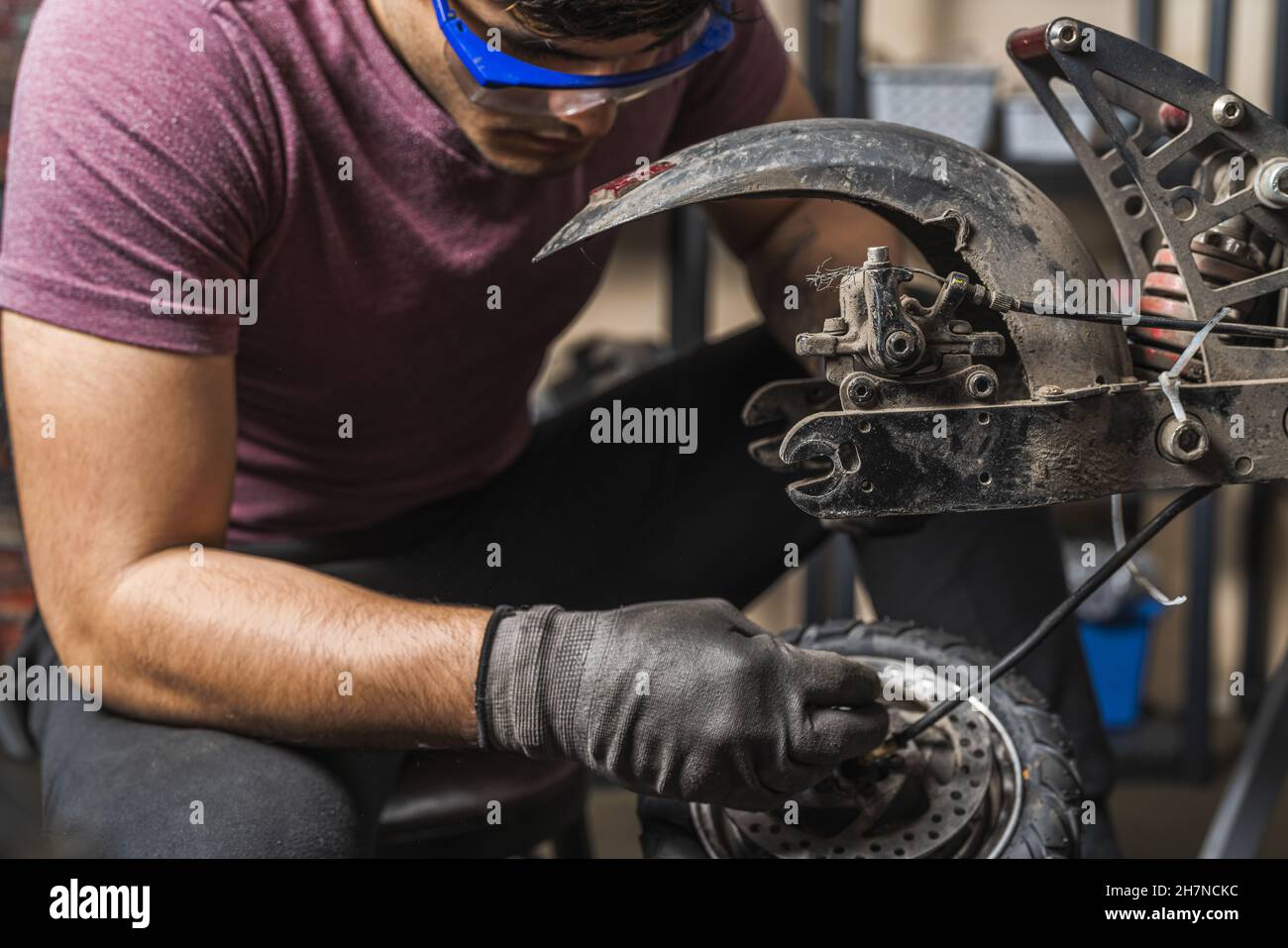 Mechanic removes the wheel of an electric scooter for inspection in his ...