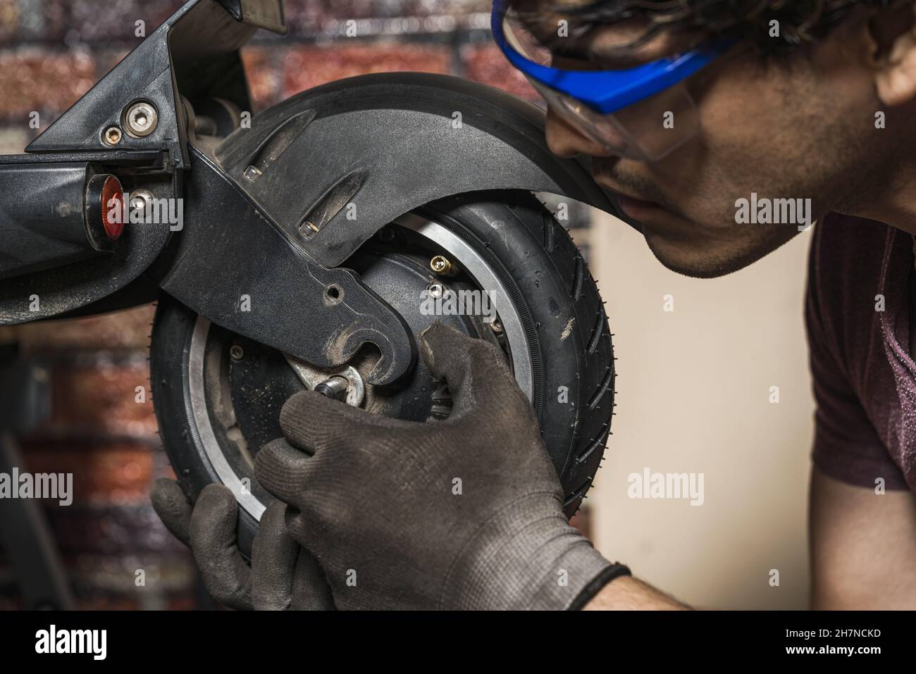 Mechanic with safety goggles putting the wheel of an electric scooter ...