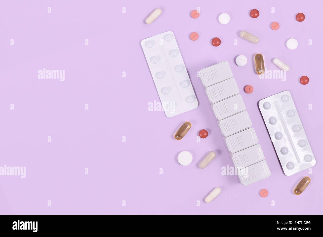 Pills, capsules and pill box on side of violet background with copy ...