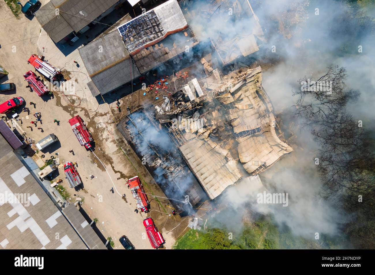 Aerial view of firefighters extinguishing ruined building on fire with ...