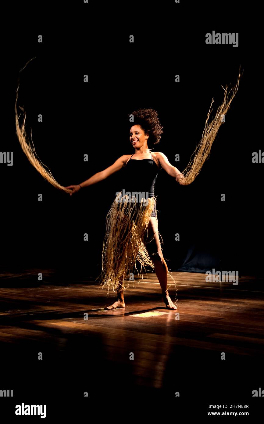 Contemporary dancer dancing in theater with black background and straw ...
