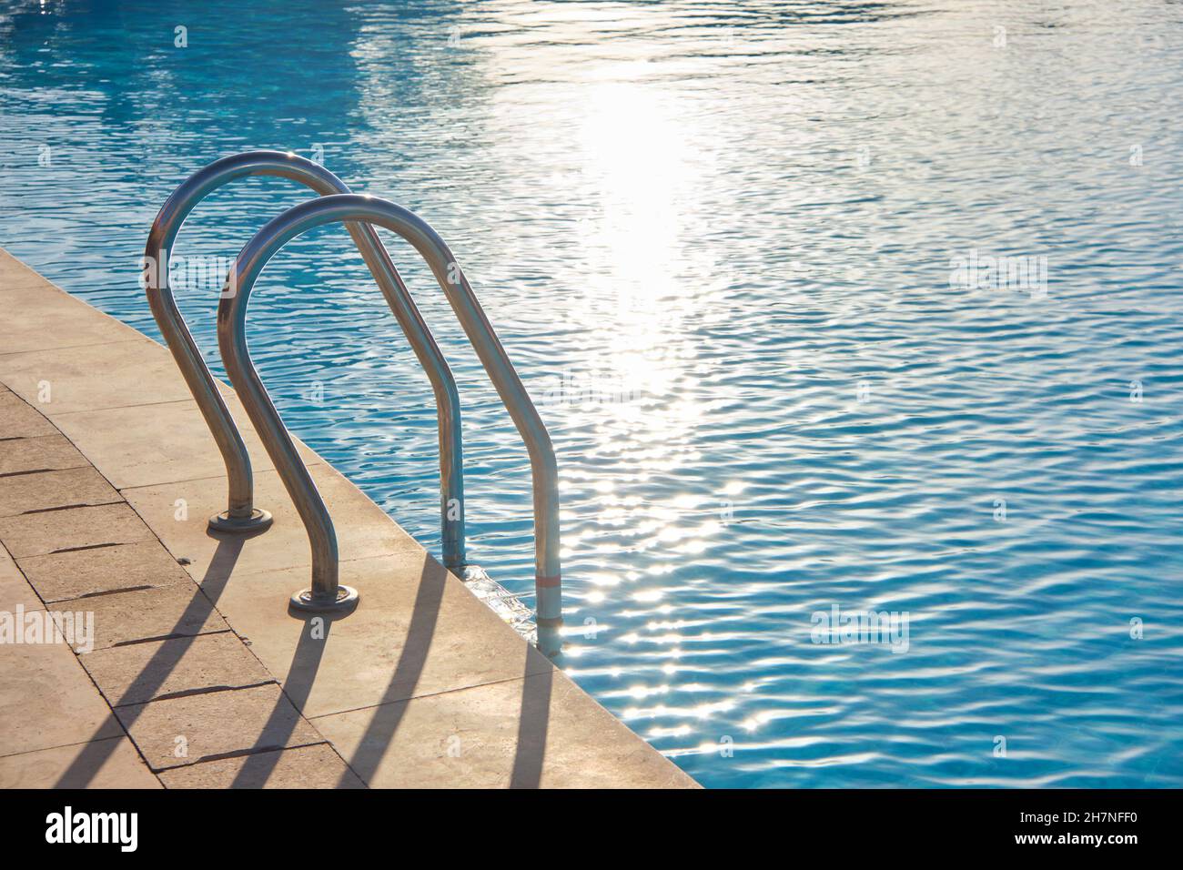 Close up of swimming pool stainless steel handrail descending into ...